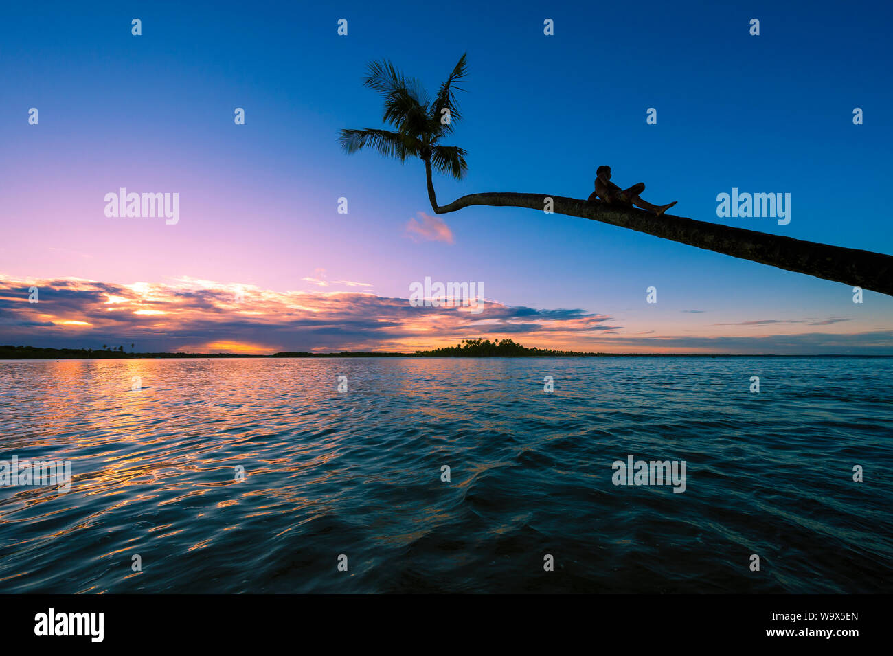 Scenic island sunset view with an unrecognizable silhouette lying on a ...