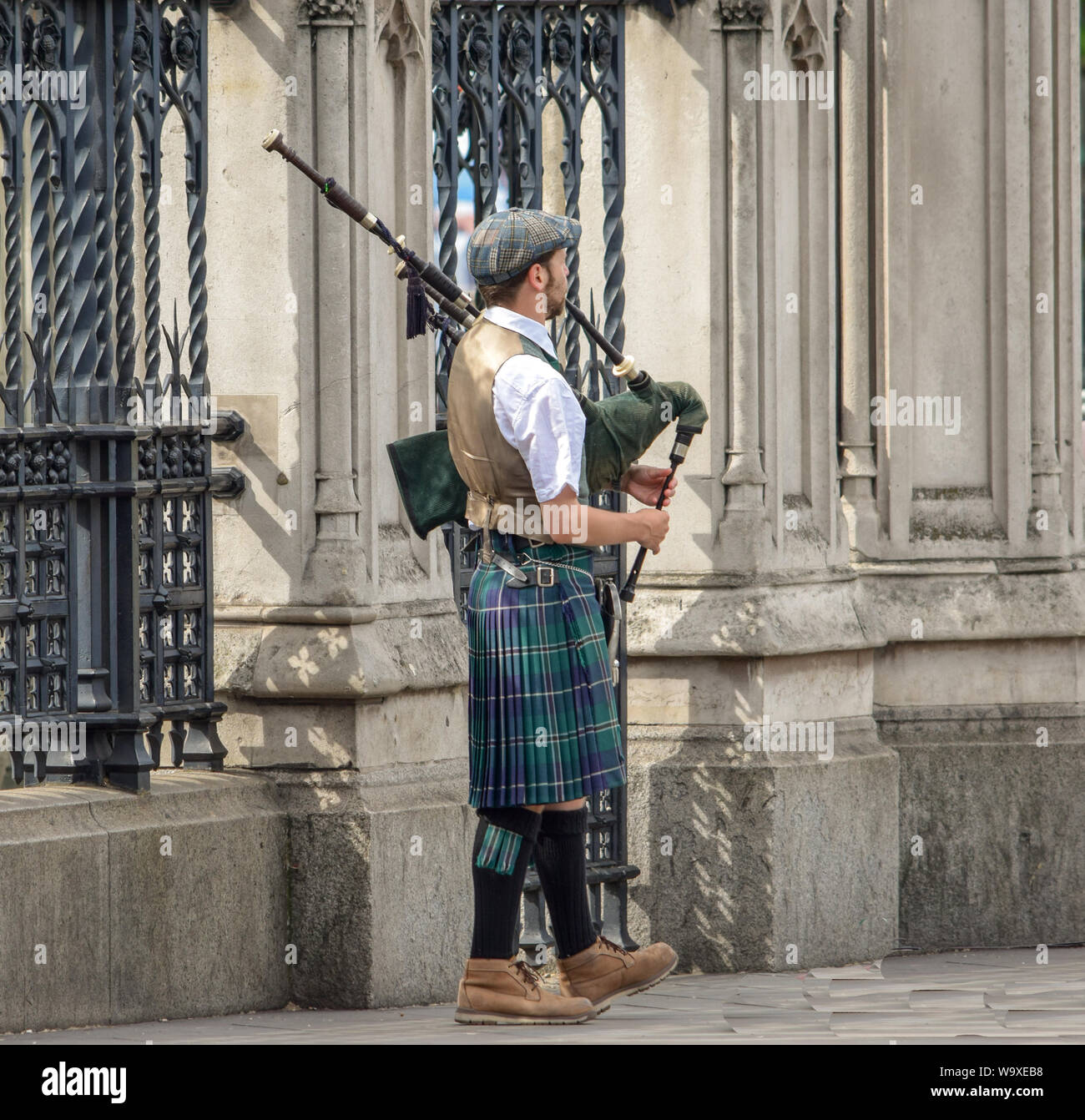 Scottish man in traditional dress playing bagpipe on the sidewalk Stock ...
