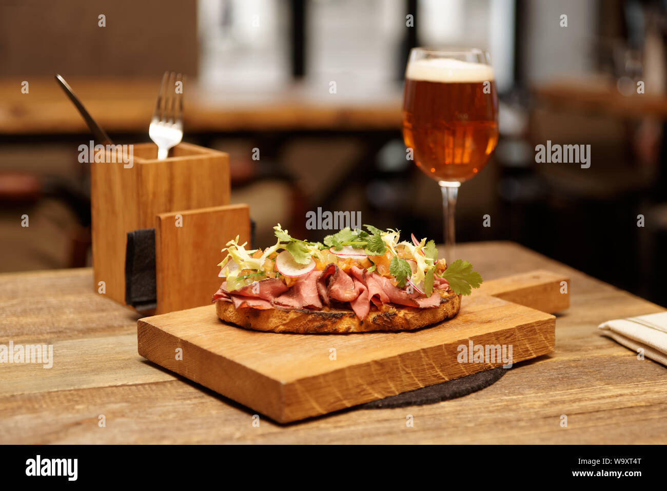 Sandwich with roast beef and glass of beer on gastronomic pub table ...