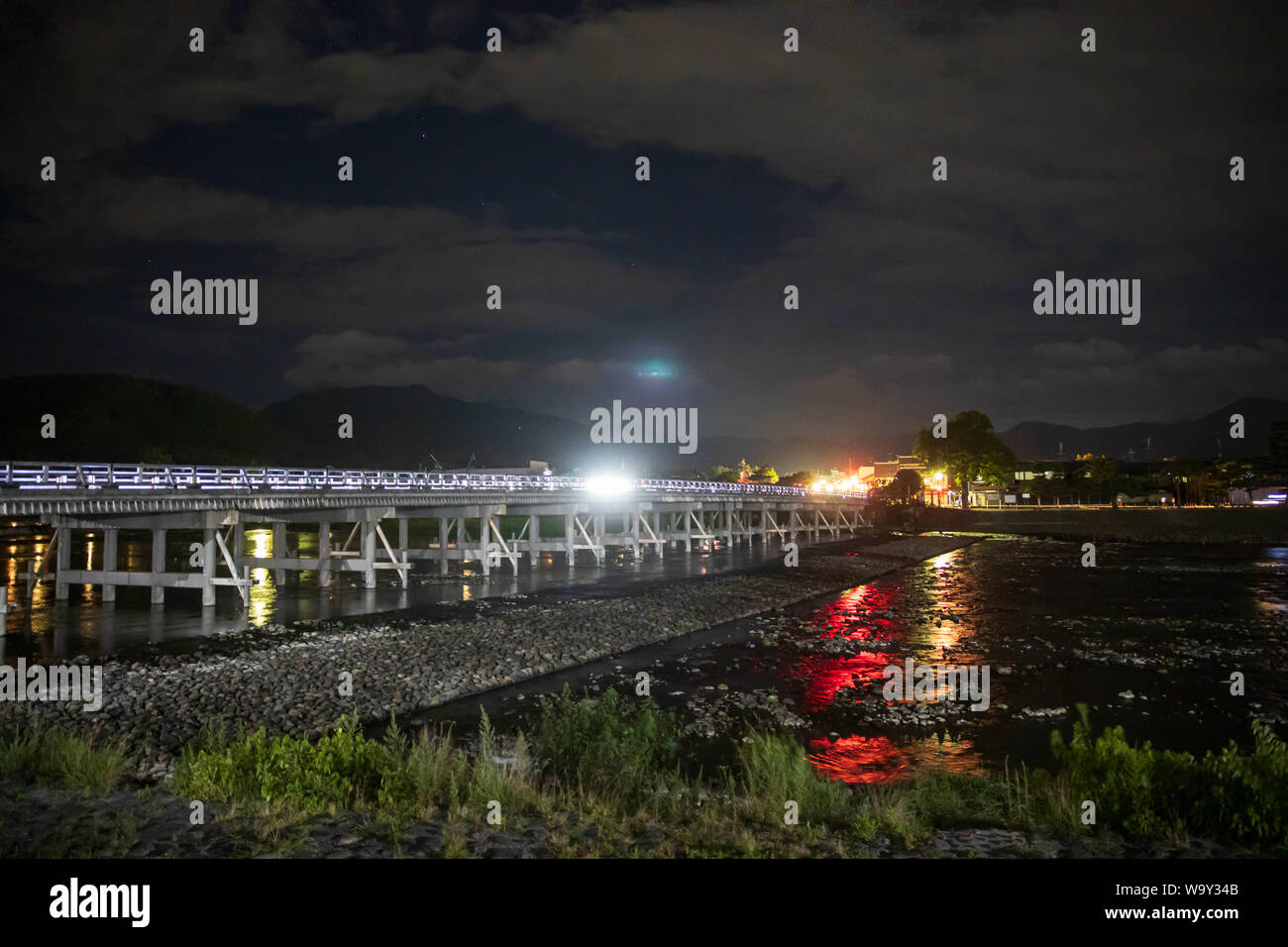 Lights from town reflect of water next to ancient Japanese wooden ...