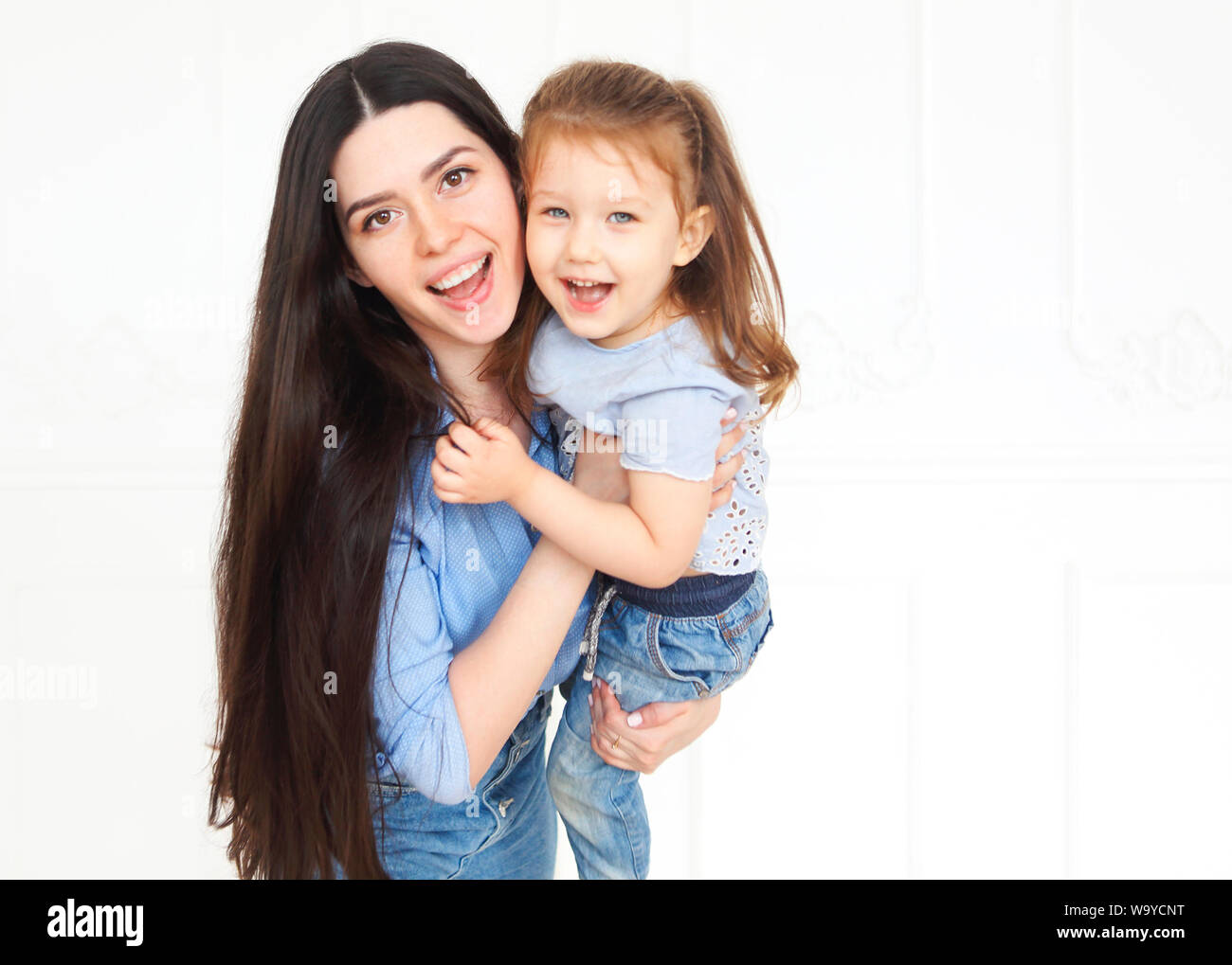 Happy young bright mother hugging her little daughter having fun ...