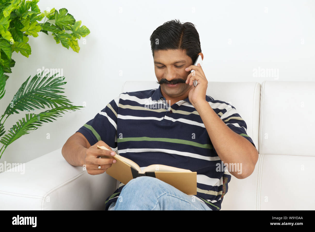 Man talking on mobile phone and holding a book Stock Photo - Alamy