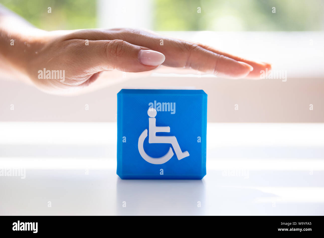 Close-up Of A Person's Hand Protecting Blue Cubic Block With Disabled ...