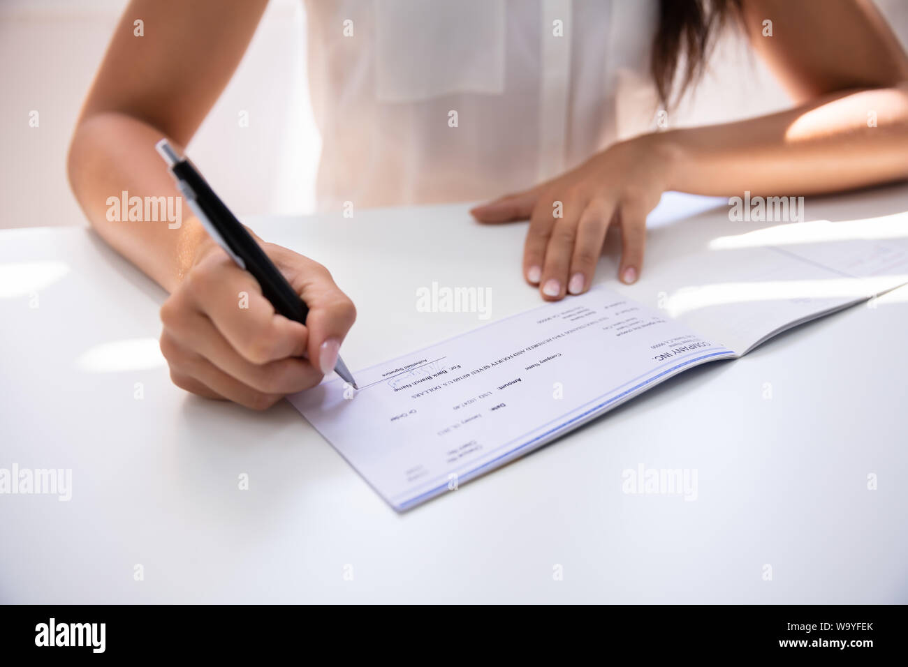 Businesswoman's Hand Signing Big Cheque With Pen Stock Photo - Alamy