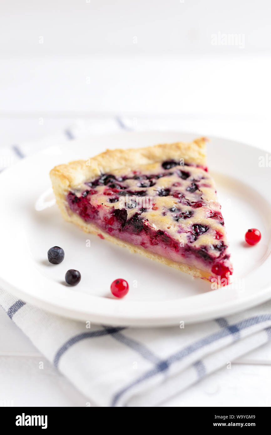 Slice of Blueberry and red currant Pie on white rustic wooden table ...