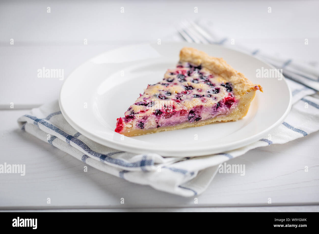 Slice of Blueberry and red currant Pie on white rustic wooden table ...