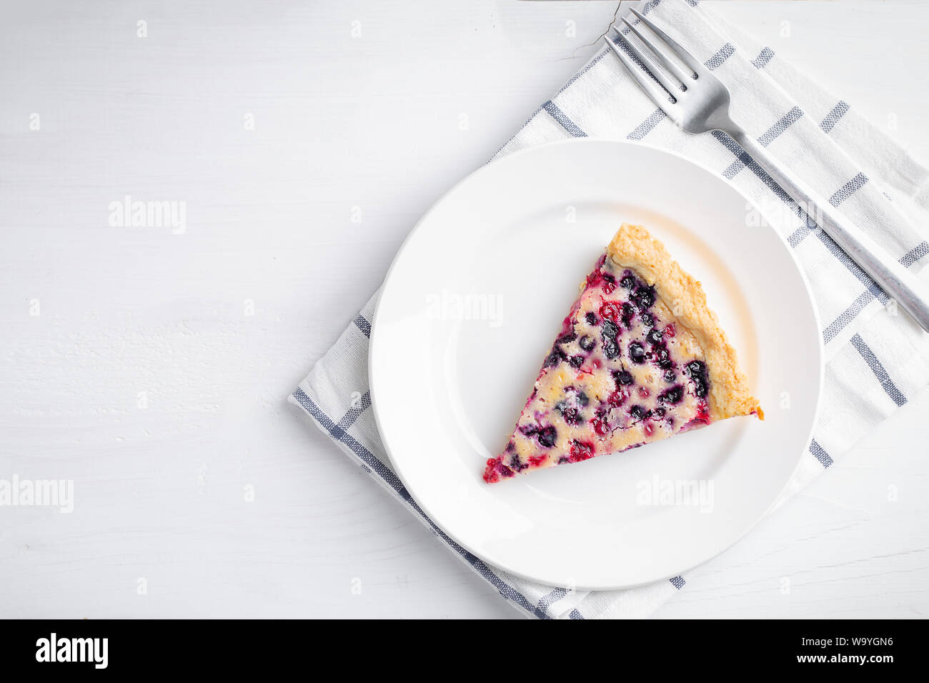 Slice of Blueberry and red currant Pie on white rustic wooden table ...