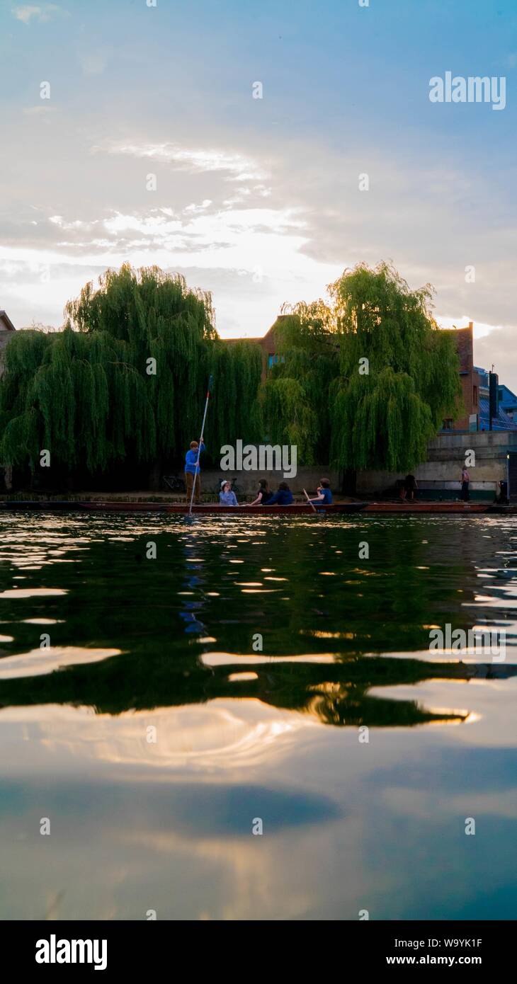 Vertical shot of people riding a canoe on the body of water with trees ...