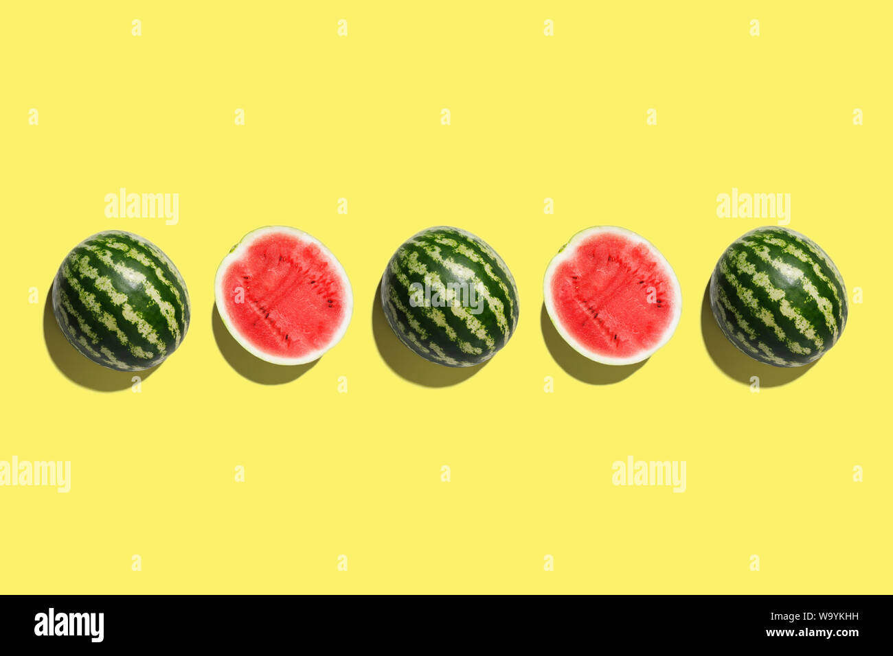 Row of fresh watermelon in center on yellow backgrond Stock Photo - Alamy