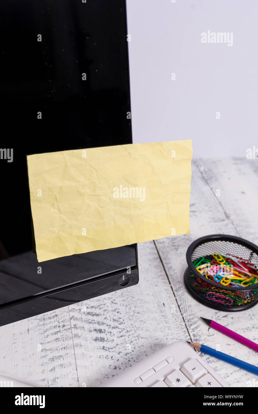 Note paper taped to black computer screen near keyboard and stationary ...