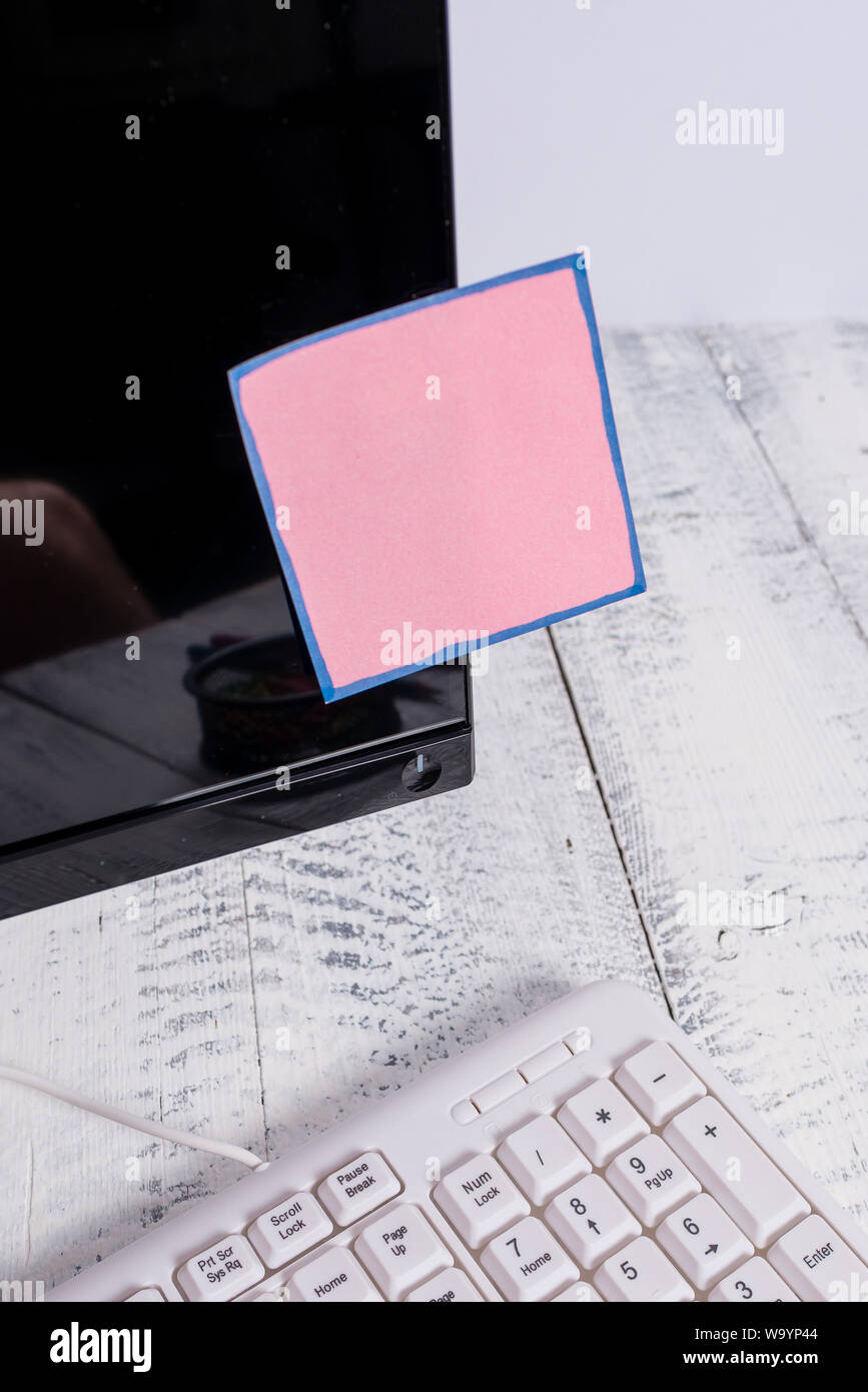 Note paper taped to black computer screen near keyboard and stationary ...