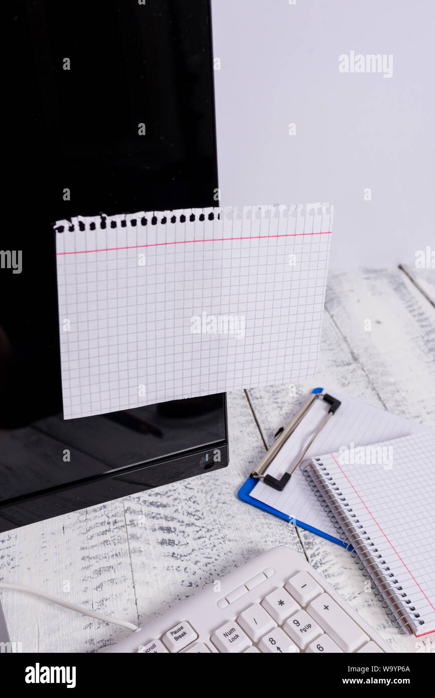 Note paper taped to black computer screen near keyboard and stationary ...