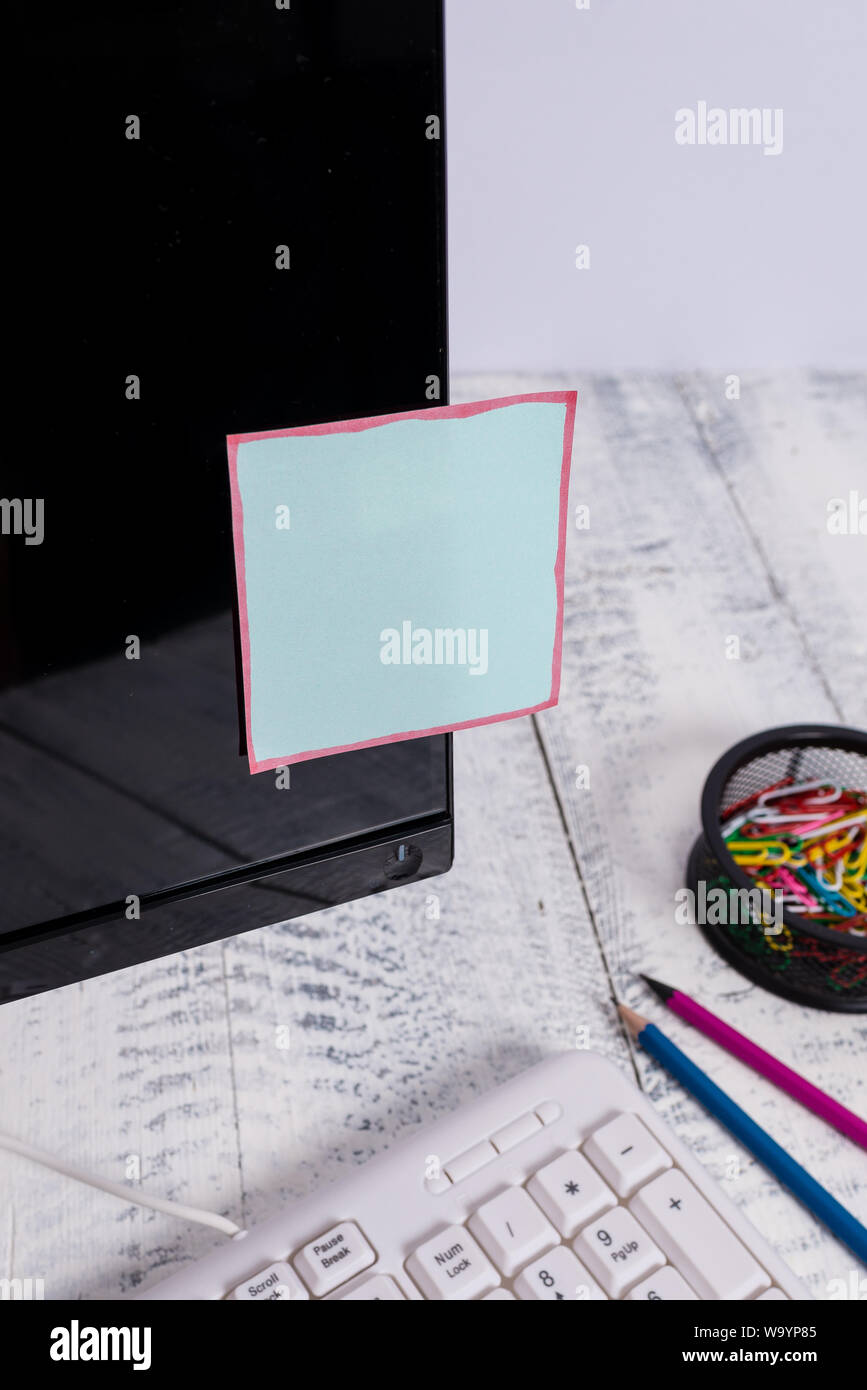 Note paper taped to black computer screen near keyboard and stationary ...
