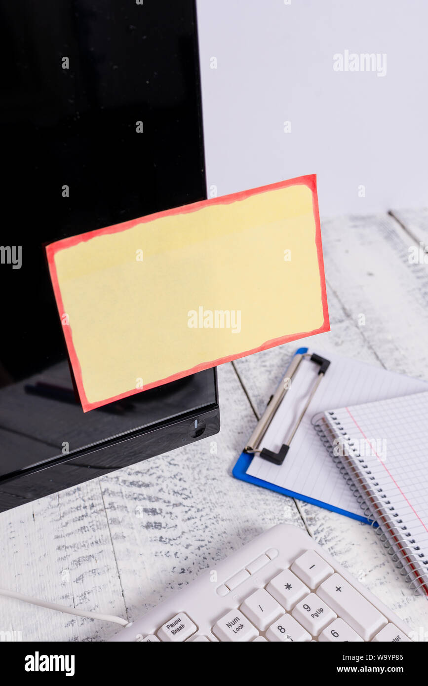 Note paper taped to black computer screen near keyboard and stationary ...