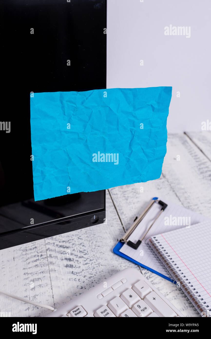 Note paper taped to black computer screen near keyboard and stationary ...
