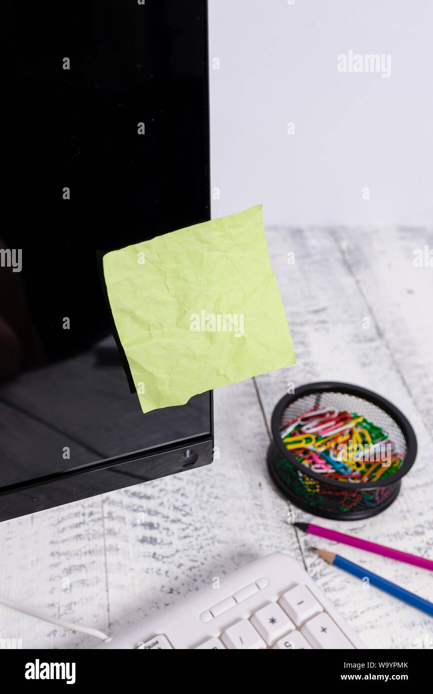 Note paper taped to black computer screen near keyboard and stationary ...