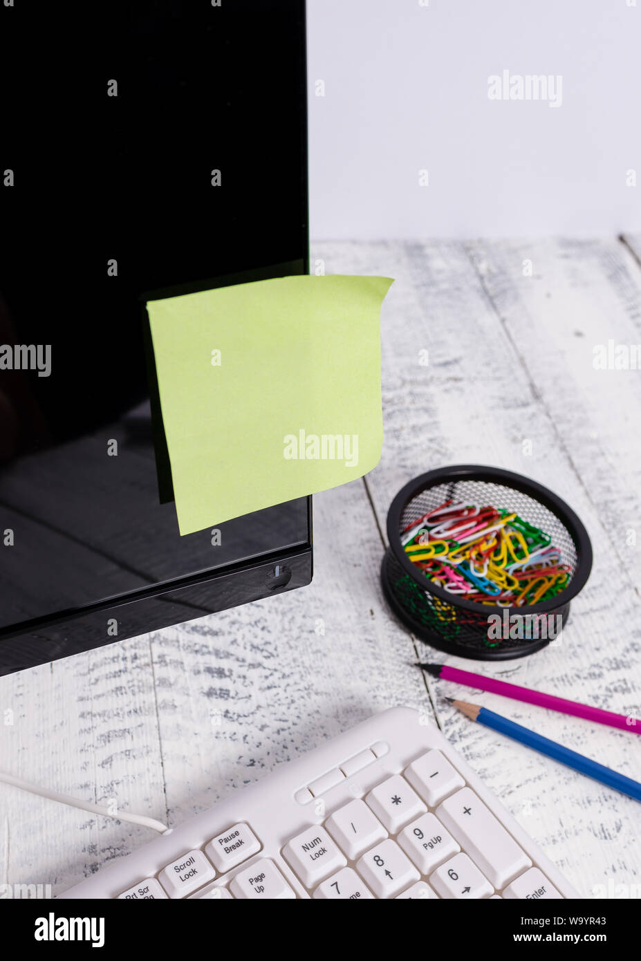 Note paper taped to black computer screen near keyboard and stationary ...