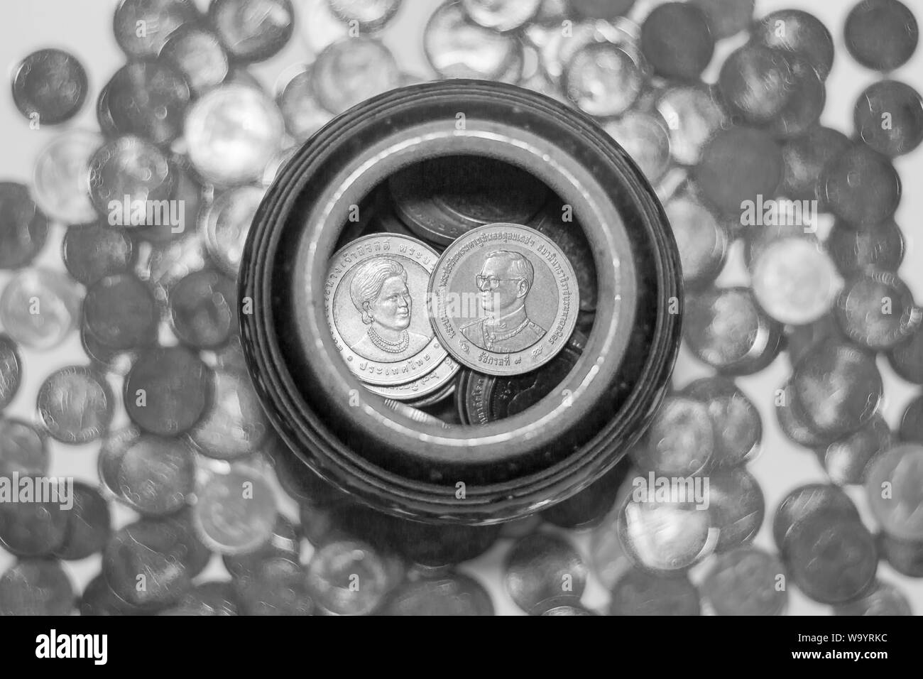 White and black thai coins in a jar and a king and queen on a coin ...