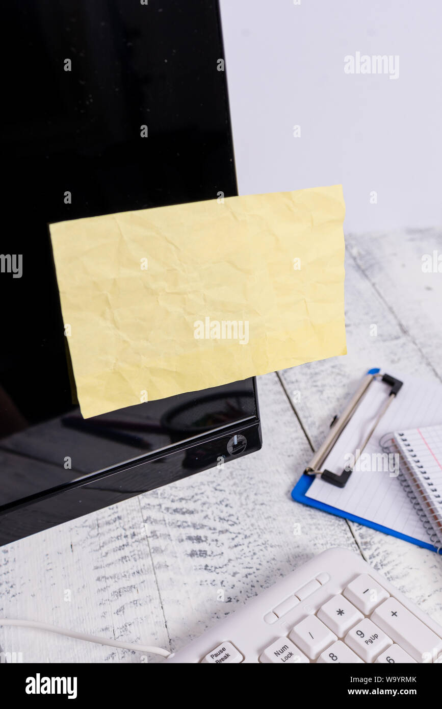 Note paper taped to black computer screen near keyboard and stationary ...