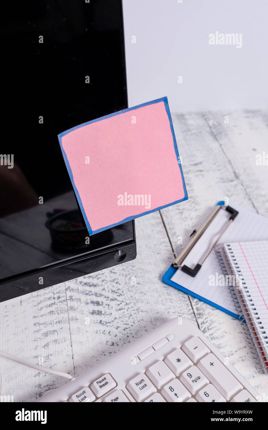Note paper taped to black computer screen near keyboard and stationary ...