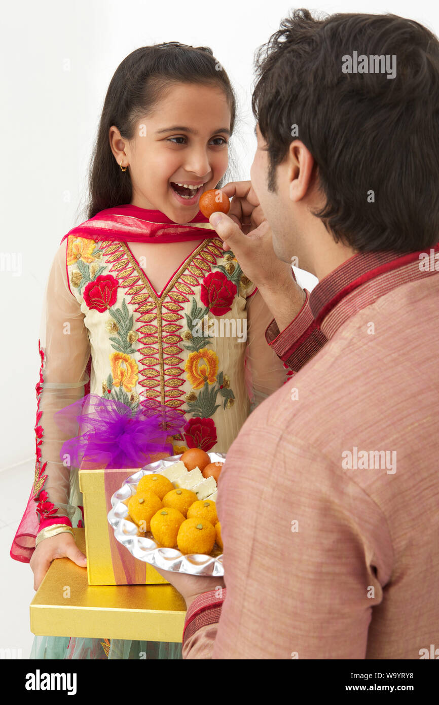 Man feeding sweets to his daughter Stock Photo - Alamy