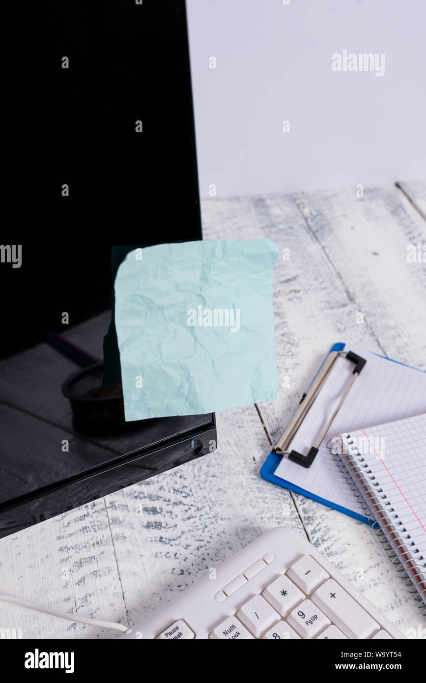 Note paper taped to black computer screen near keyboard and stationary ...