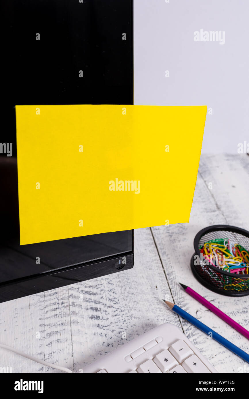 Note paper taped to black computer screen near keyboard and stationary ...