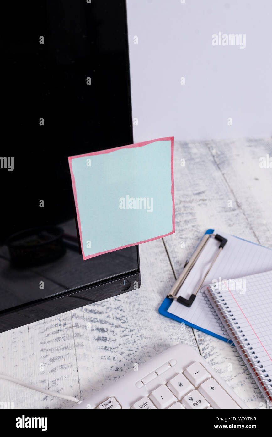 Note paper taped to black computer screen near keyboard and stationary ...