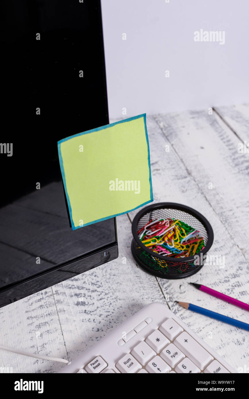 Note paper taped to black computer screen near keyboard and stationary ...