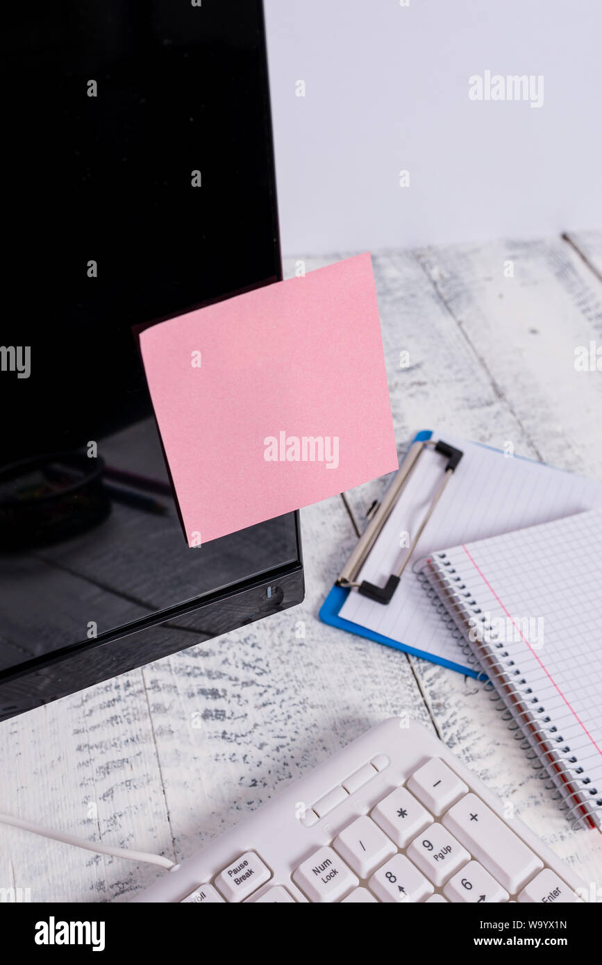 Note paper taped to black computer screen near keyboard and stationary ...