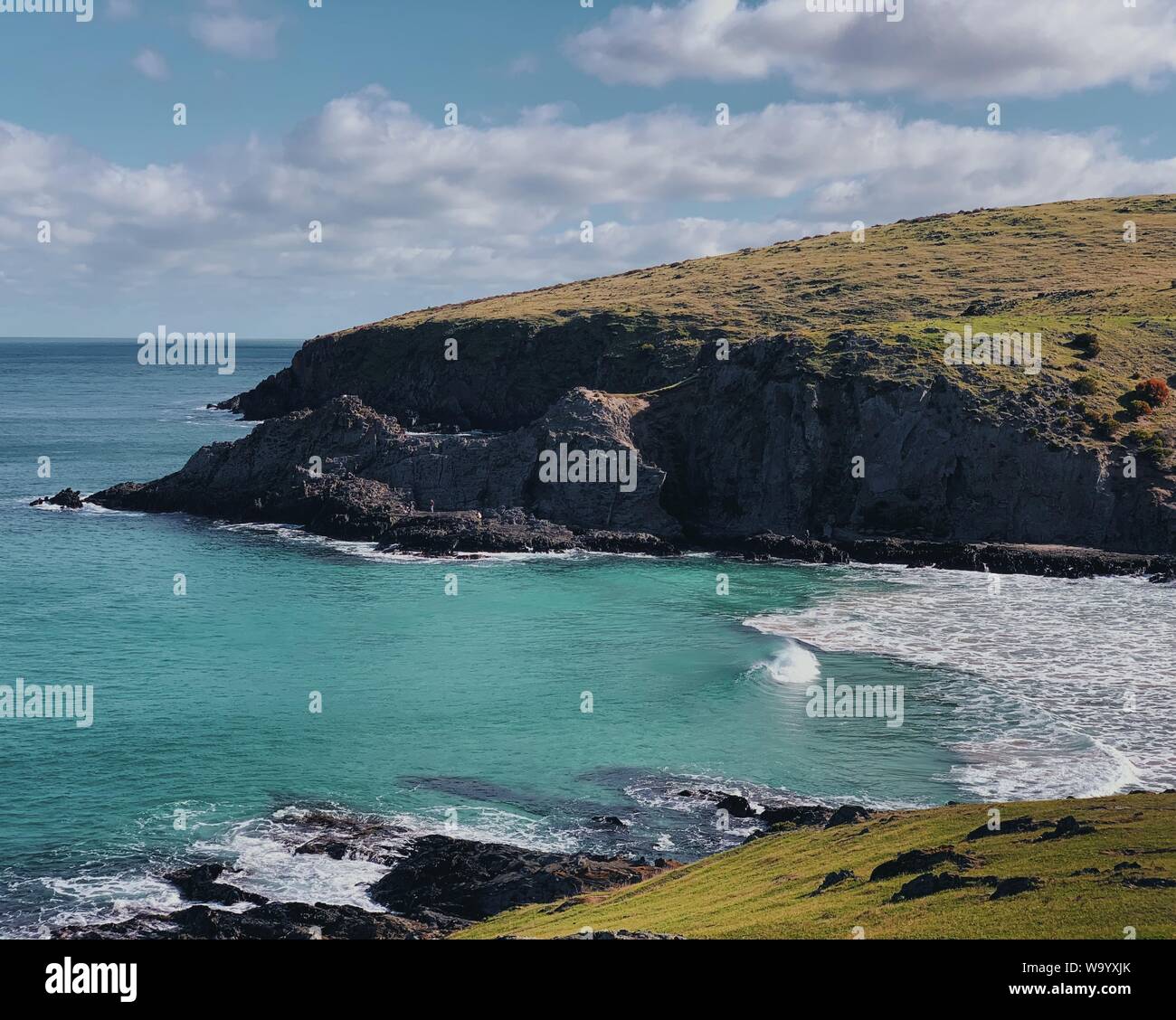 Beautiful shot of an ocean near green cliff Stock Photo - Alamy