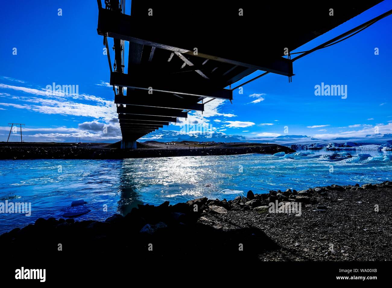 Wide shot of iced sea with ice shards and cubes under a black bridge ...
