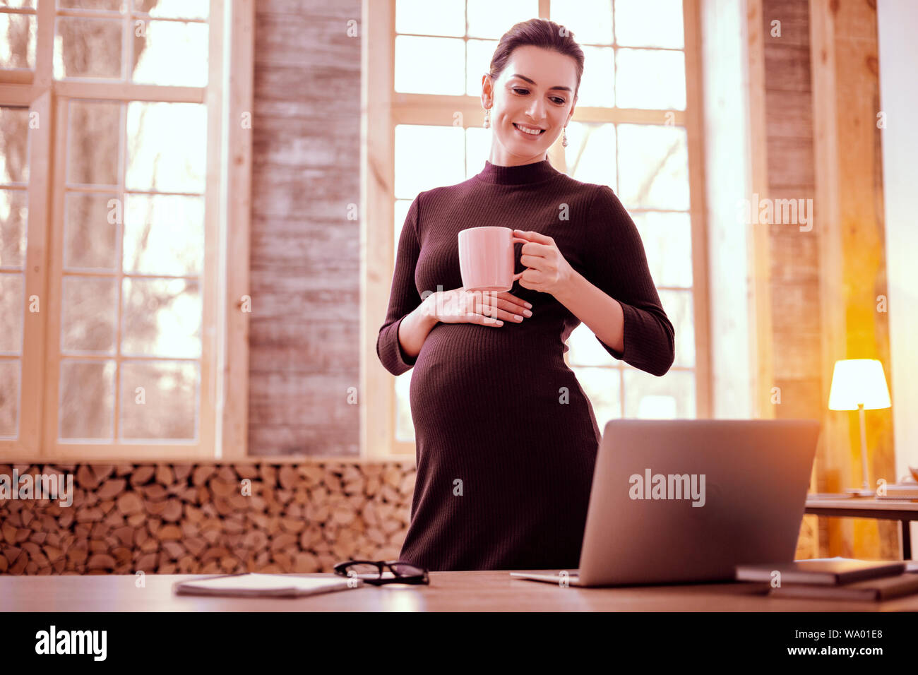 Baby expectation. Cheerful young woman keeping smile on her face while ...