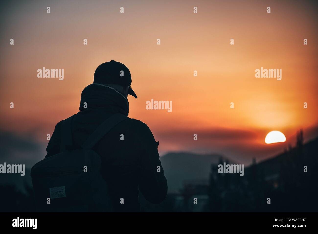 Behind shot of a mysterious male in a baseball cap and a backpack ...