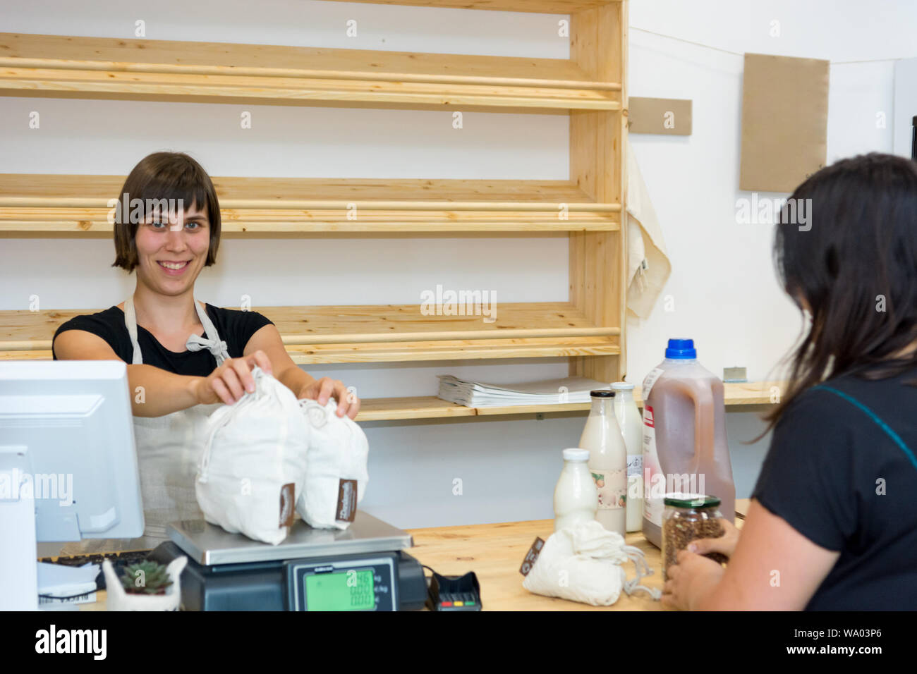 Female shop assistant serving a customer at a desk Stock Photo - Alamy