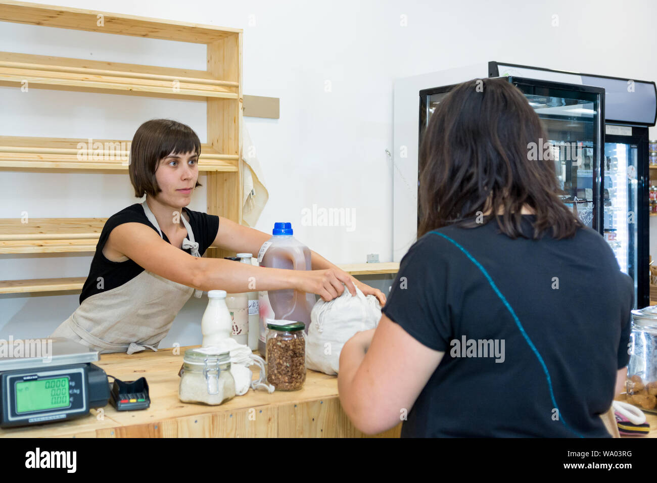 Female shop assistant serving a customer at a desk Stock Photo - Alamy