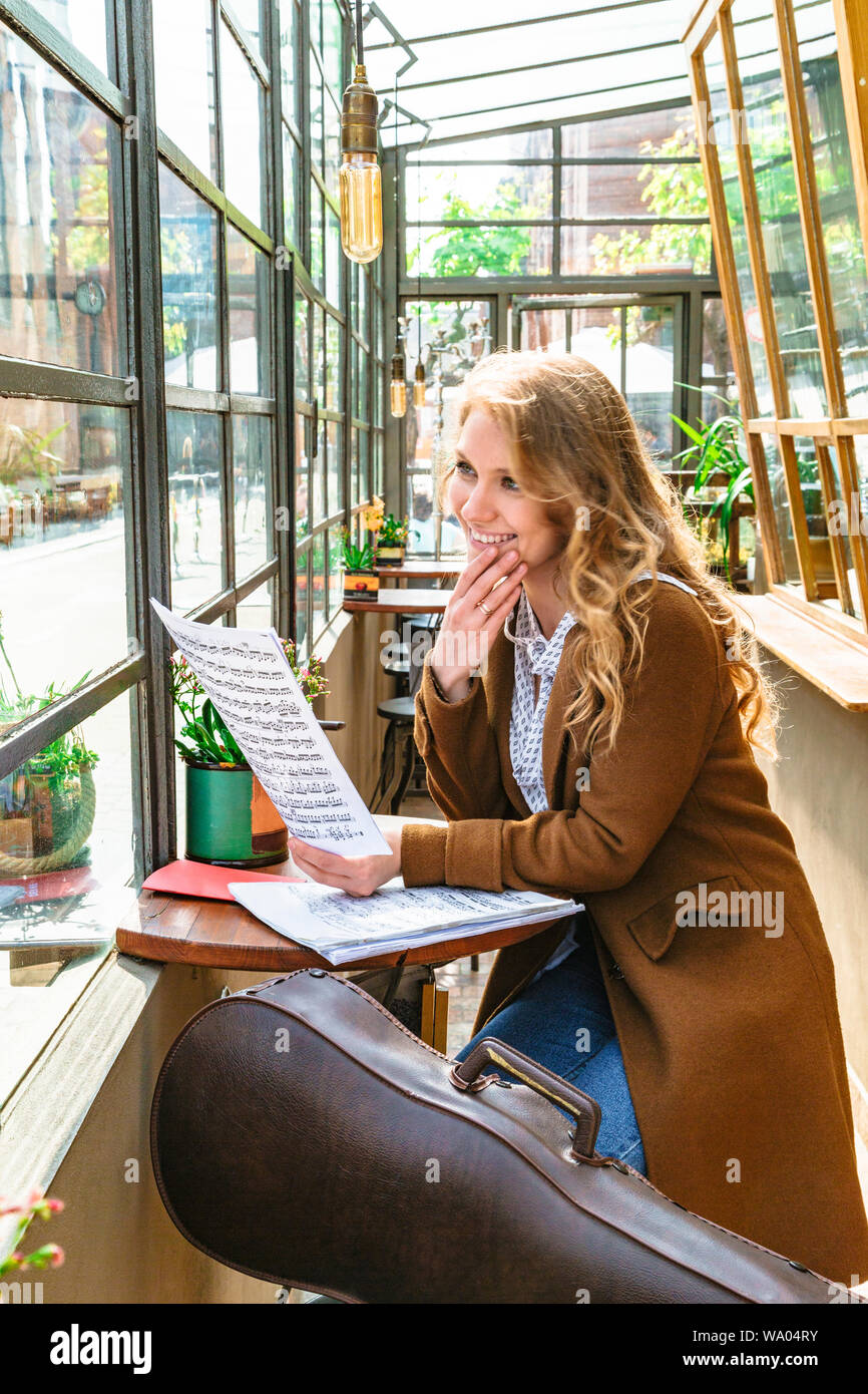 Girl reading notes for violin part sitting in cafe Stock Photo - Alamy