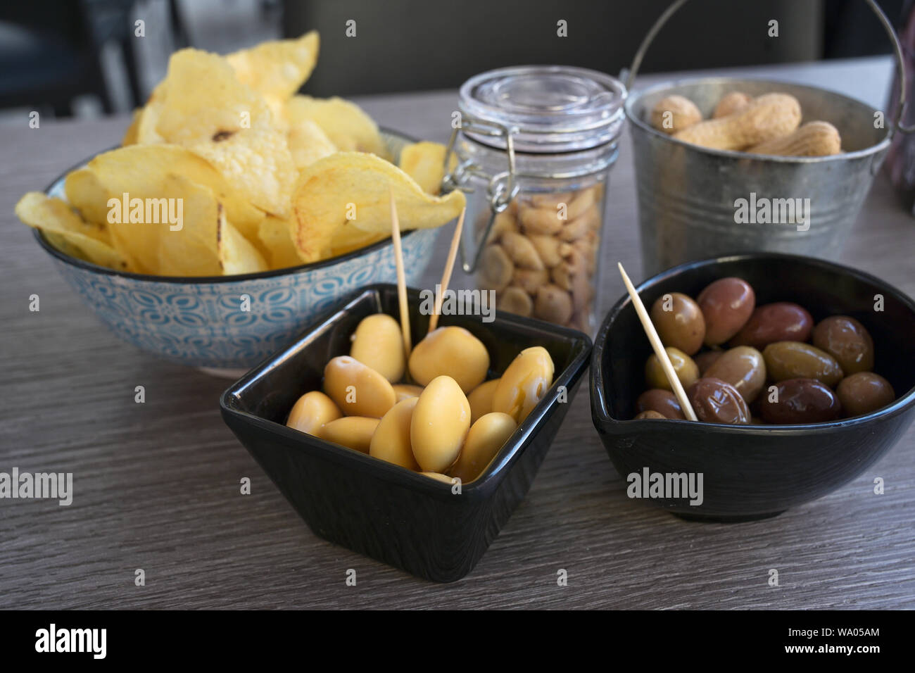 small snacks like beans, olives, nuts and chips on a table in an ...