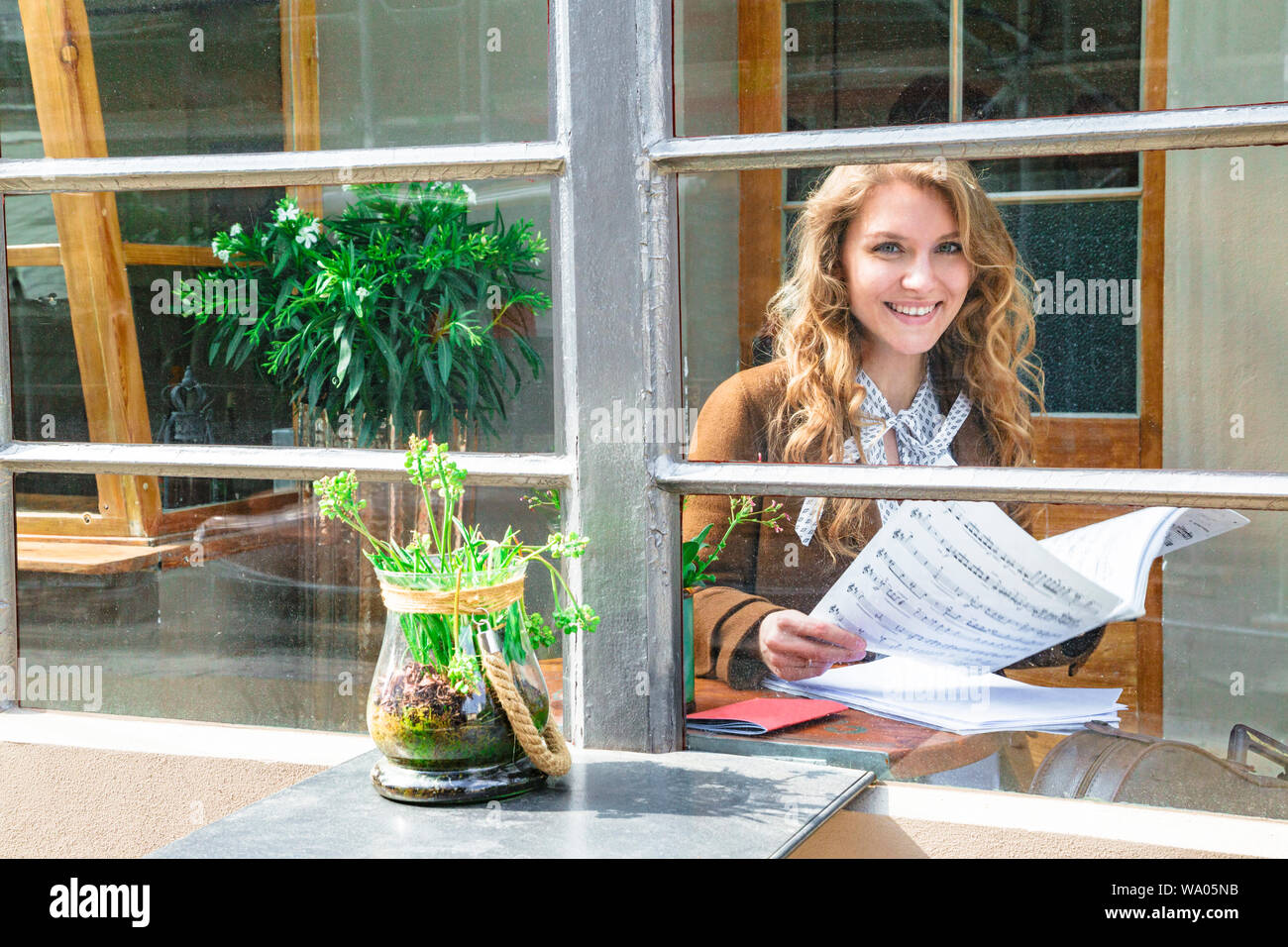 Girl sitting at window with notes in her hands Stock Photo - Alamy