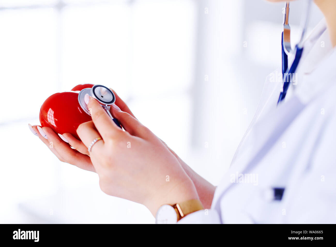 Doctor in a hospital examines a heart with a stethoscope. Workplace ...