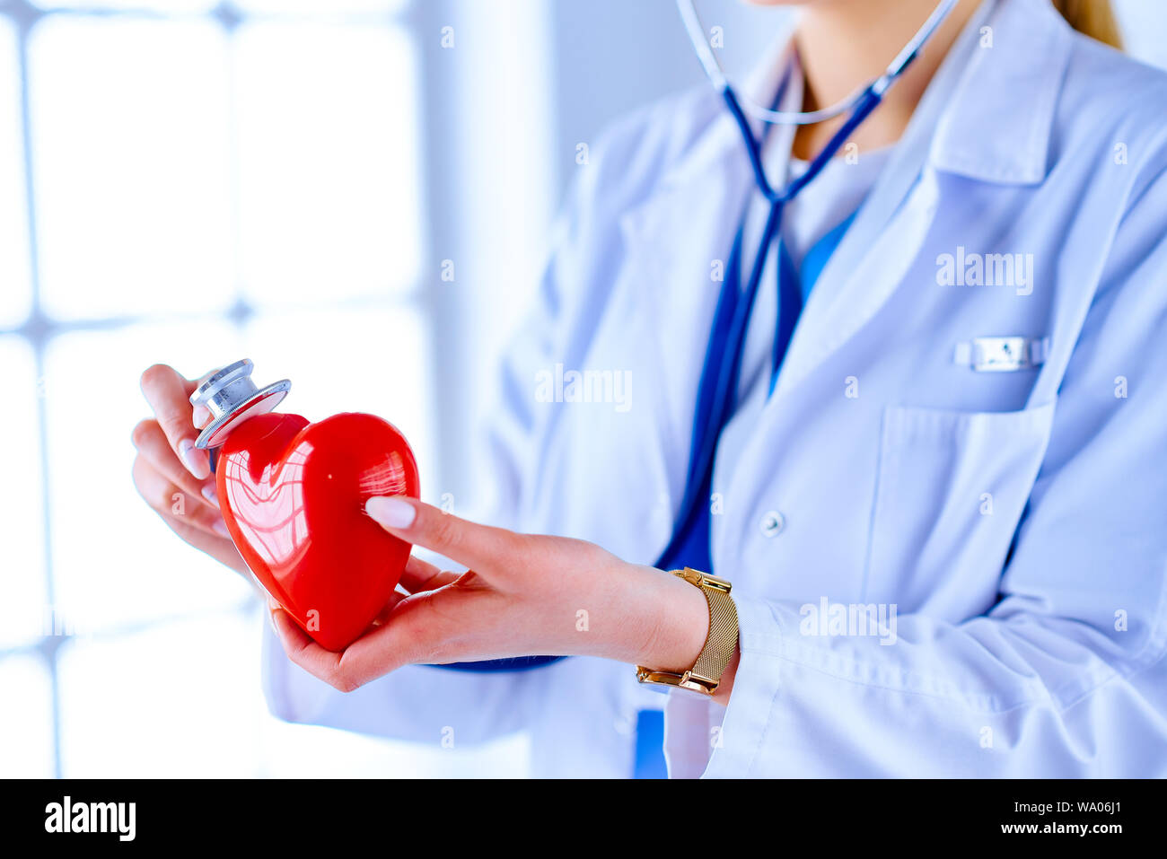 Female doctor with stethoscope examining red heart. Health, medicine ...