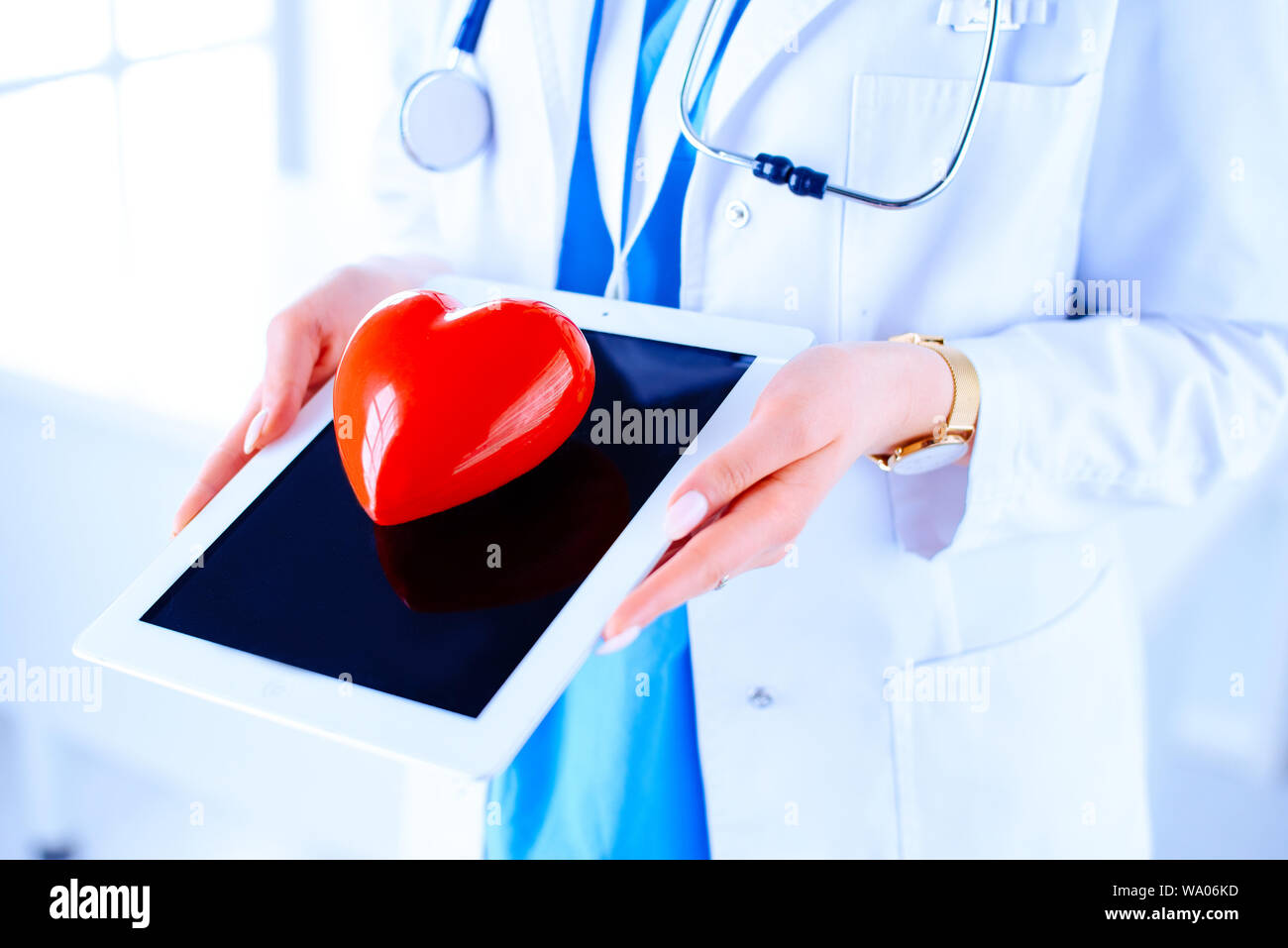 Doctor cardiologist with stethoscope using digital tablet and holding ...