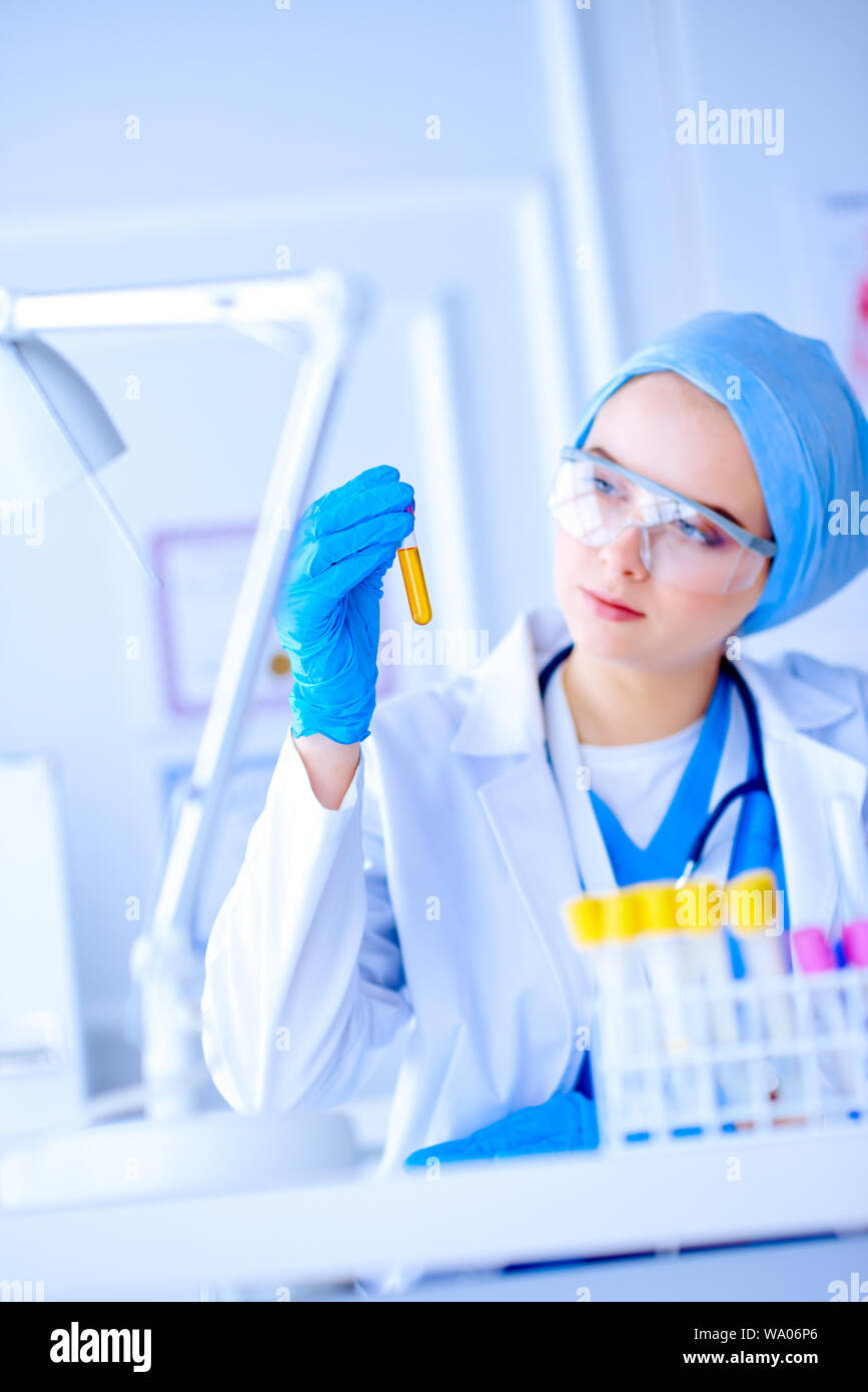 Woman holding test tube in laboratory. Researcher is surrounded by ...