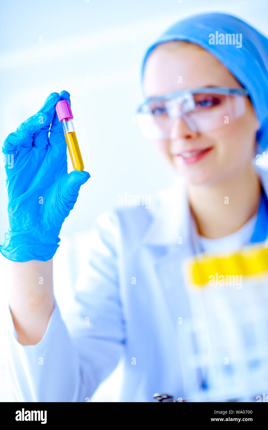 Woman holding test tube. Researcher is surrounded by medical vials and ...