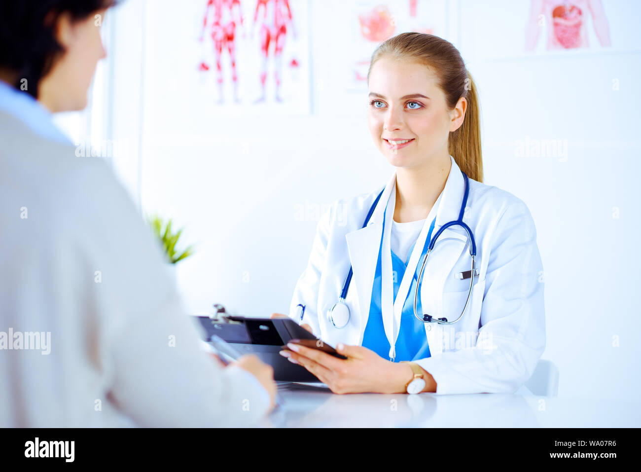 Female doctor consulting patient while filling up an application form ...