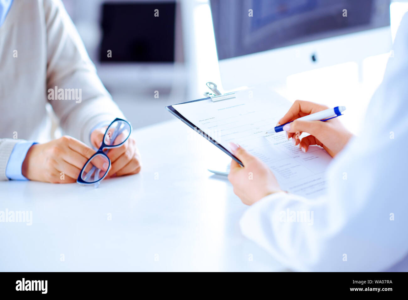 Close up of patient and doctor taking notes in medical office Stock ...