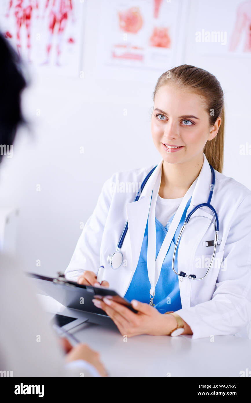 Female doctor consulting patient while filling up an application form ...