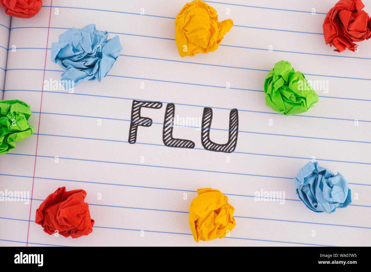 Flu. The word Flu on notebook sheet with some colorful crumpled paper ...