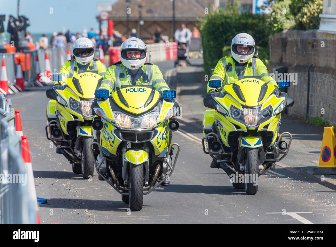 three mounted police officers on motorcycles riding together along a ...