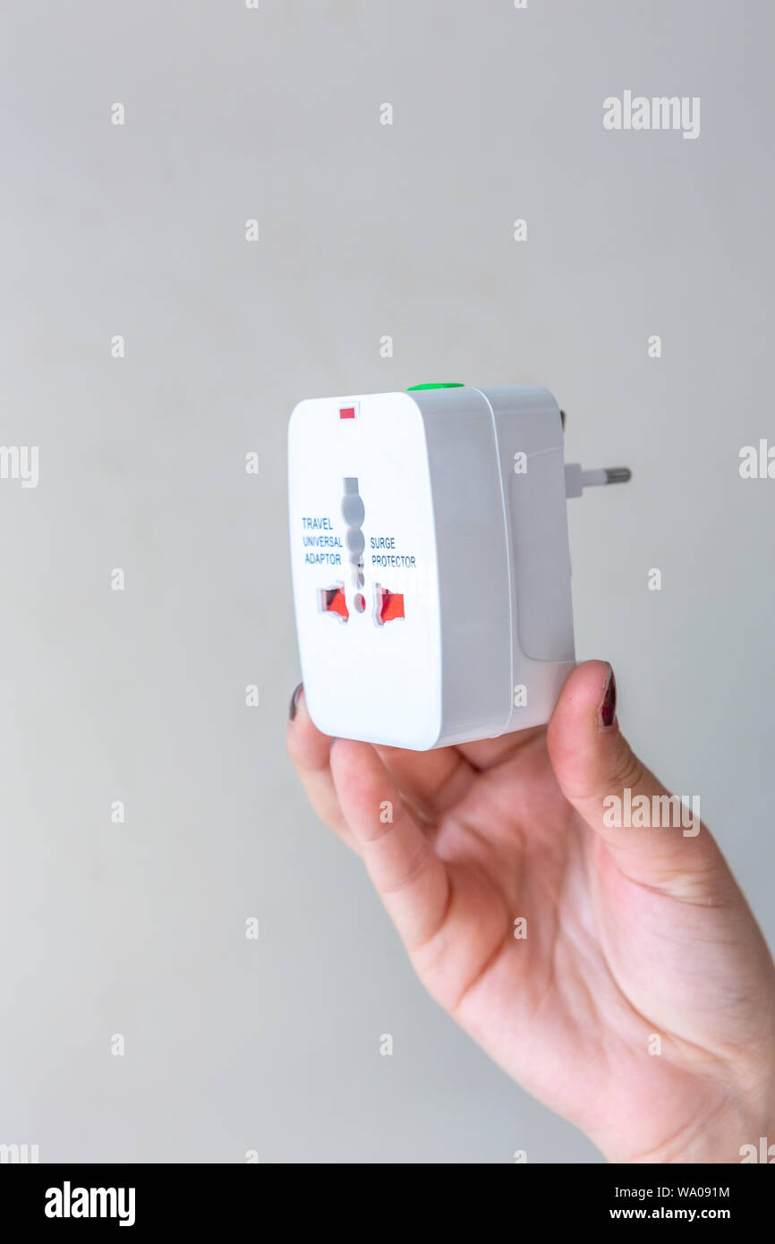Close up of woman hand holding universal electric socket plug adapters ...